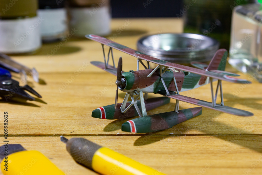 Plastic model WW2 biplane with scale model tools on wooden workbench ...