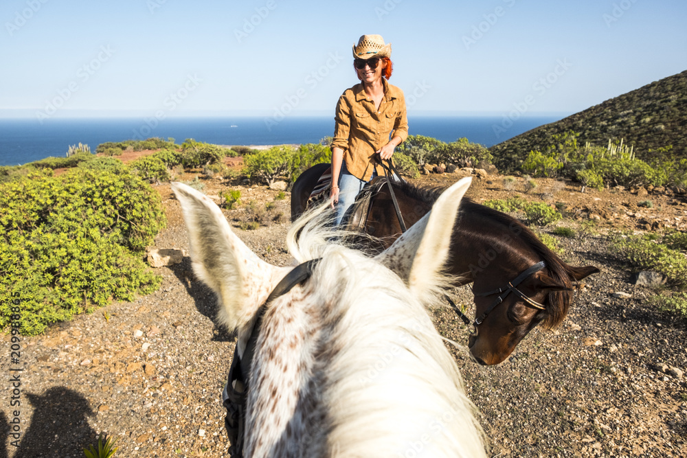 smiling beautiful red hair lady young ride a horse. view from another ...