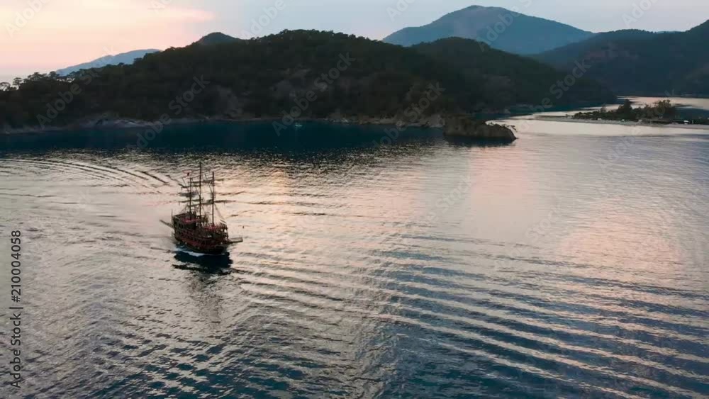 Large pirate ship moving past a rocky coastline at sunset Stock Video ...