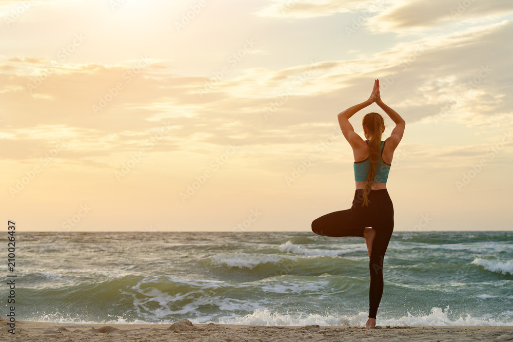 Girl on sea beach practicing yoga. Back view. Beautiful sunlight Stock ...