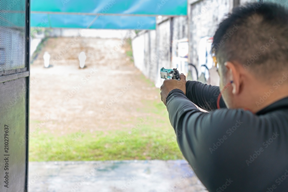 Rear view of a Man Shooting with Gun at Target in Shooting Range. Man ...