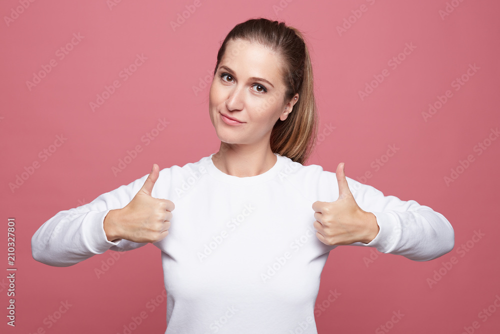 Portrait of a happy young successful woman giving two thumbs up gesture ...