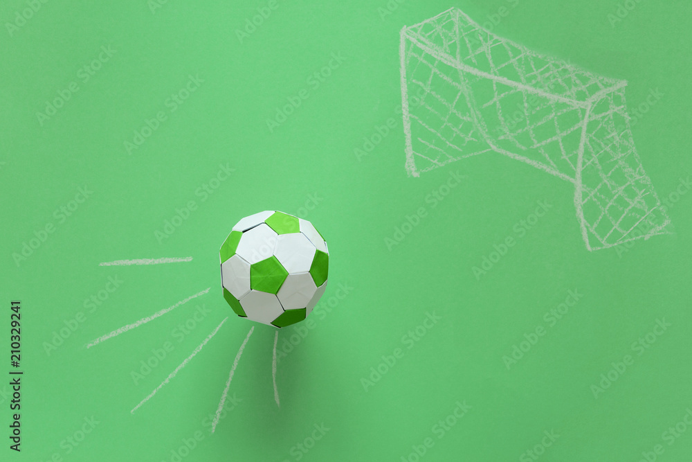 Paper soccer ball flying into goal painted by chalk on green background ...