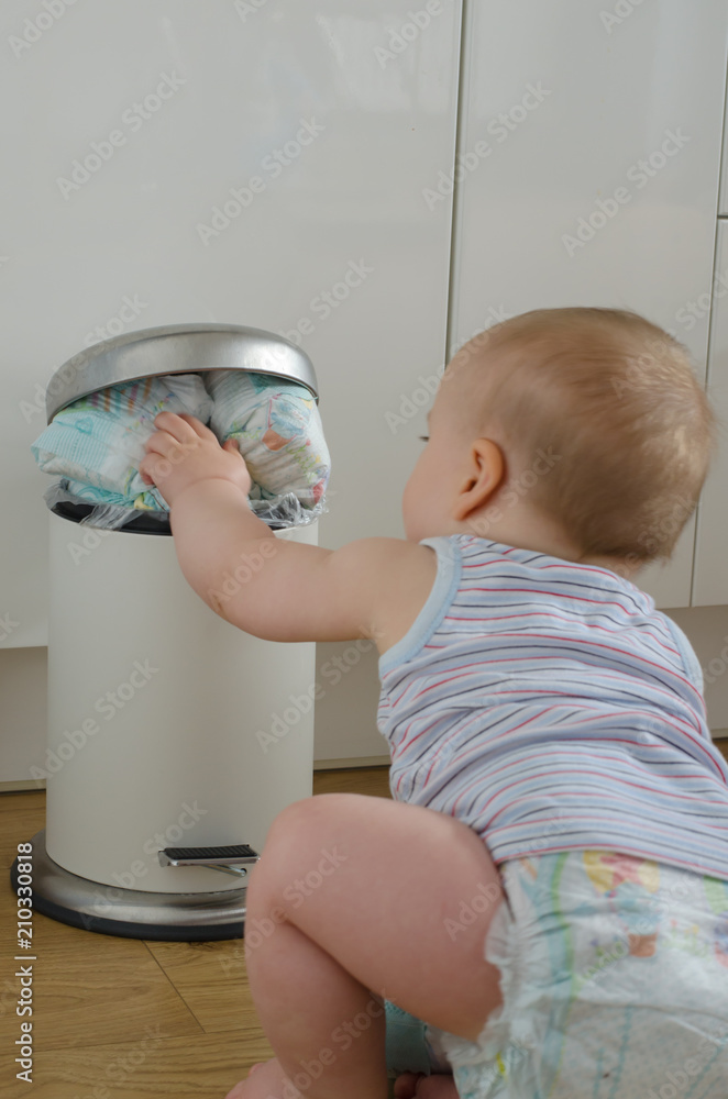baby touching the garbage can full of used dirty diapers. view from ...