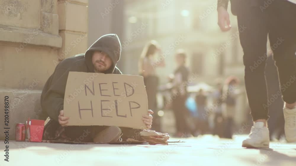 homeless man sitting on street with sign people walk around sunshine ...