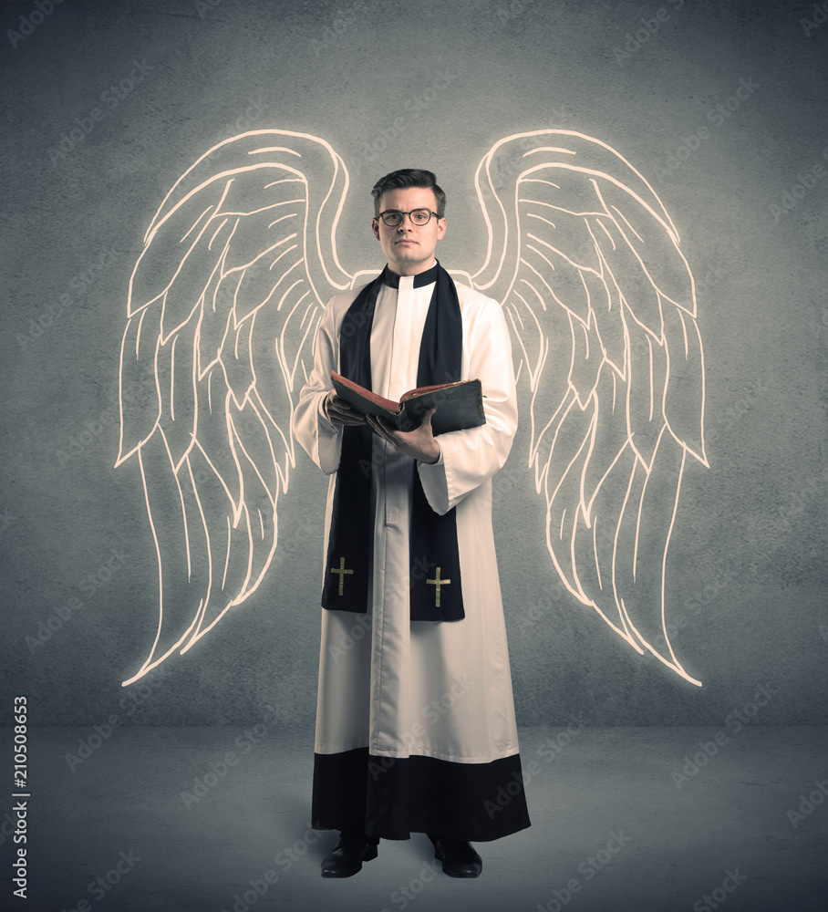 A young male priest with drawn large angel wings standing with the holy ...