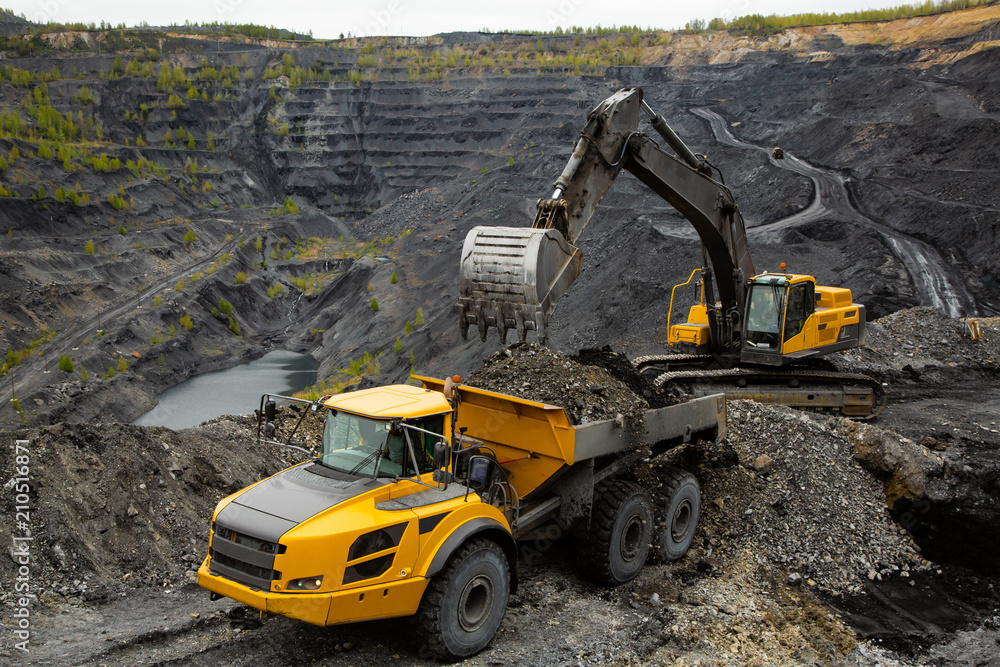 Excavator loads coal in a articulated dump truck. Heavy mining industry ...