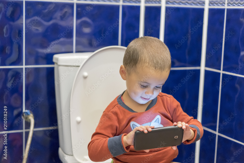 Little boy sitting on the toilet in the bathroom at home with using a ...