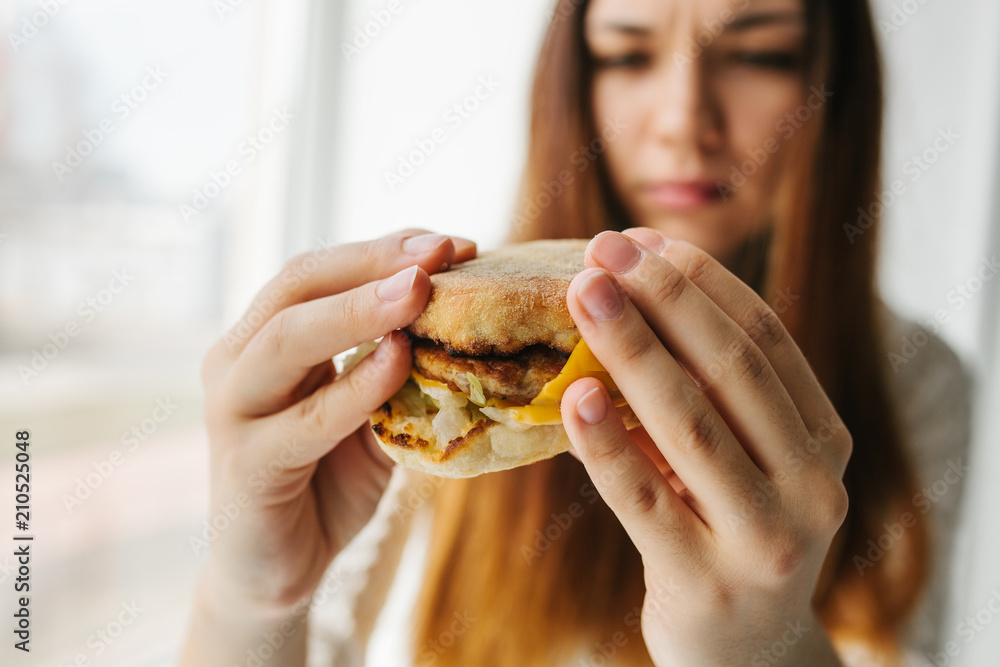 A young girl shows that she does not like a burger. Conceptual image of ...