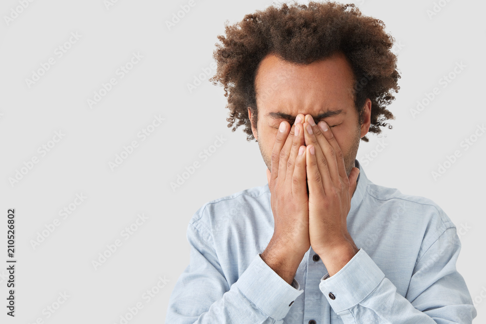 Stressed African American male covers face, cries desperately, has ...