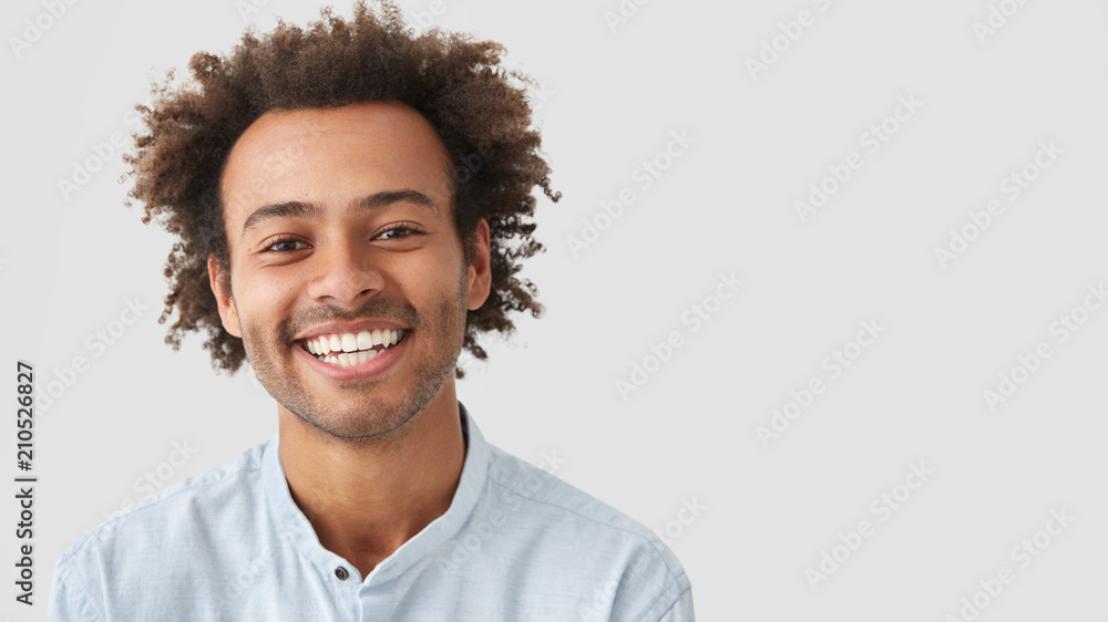 Happiness and people concept. Cheerful dark skinned glad male has broad ...