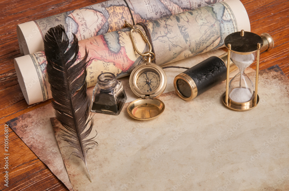 Quill pen on old paper sheets with old rolled maps and vintage items ...