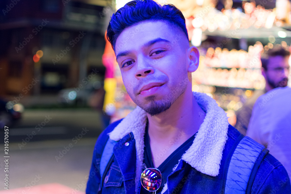 Chico joven con mirada picara con luces azules y fondo naranja Stock ...