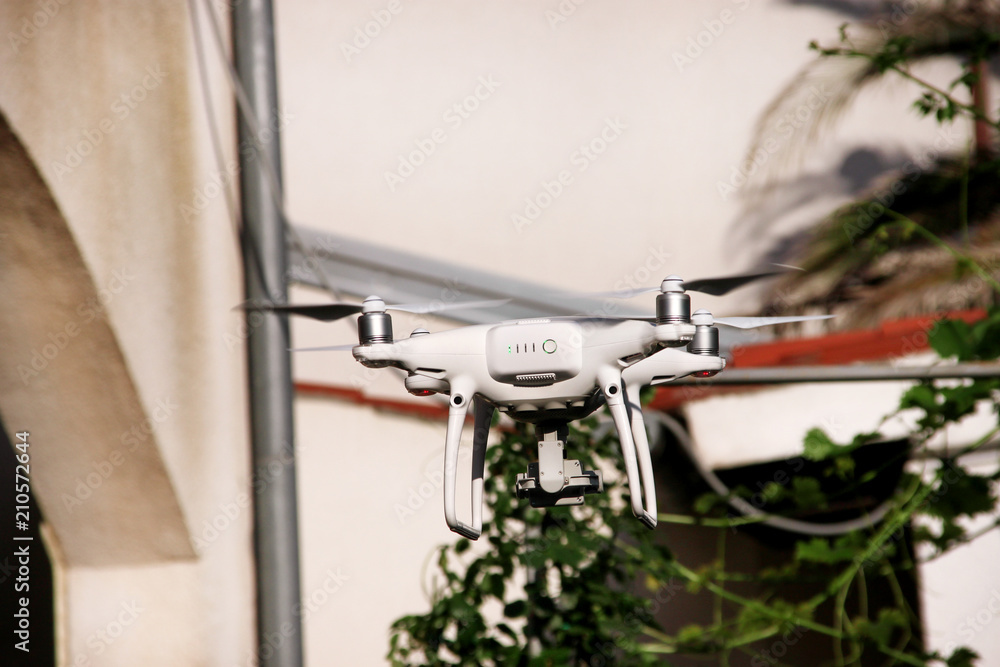 Modern White quad copter Drone with 4K digital camera is flying in the ...