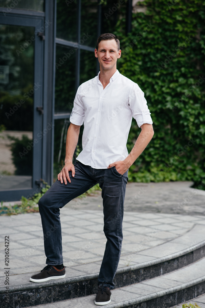 Portrait of a beautiful tall man in a white shirt on the street. Stock ...