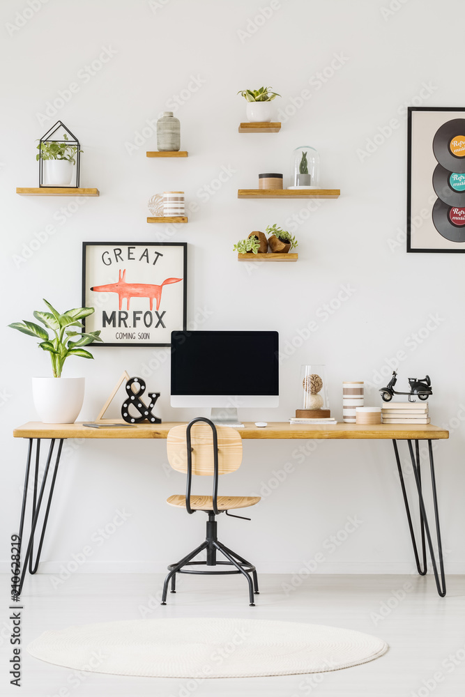 Front view of a desk with a computer, plant and books on the top ...