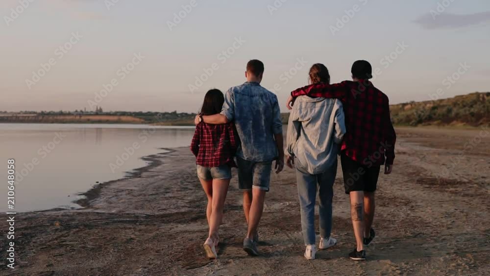 Traking footage of a young caucasian people walking on a beach. Two ...