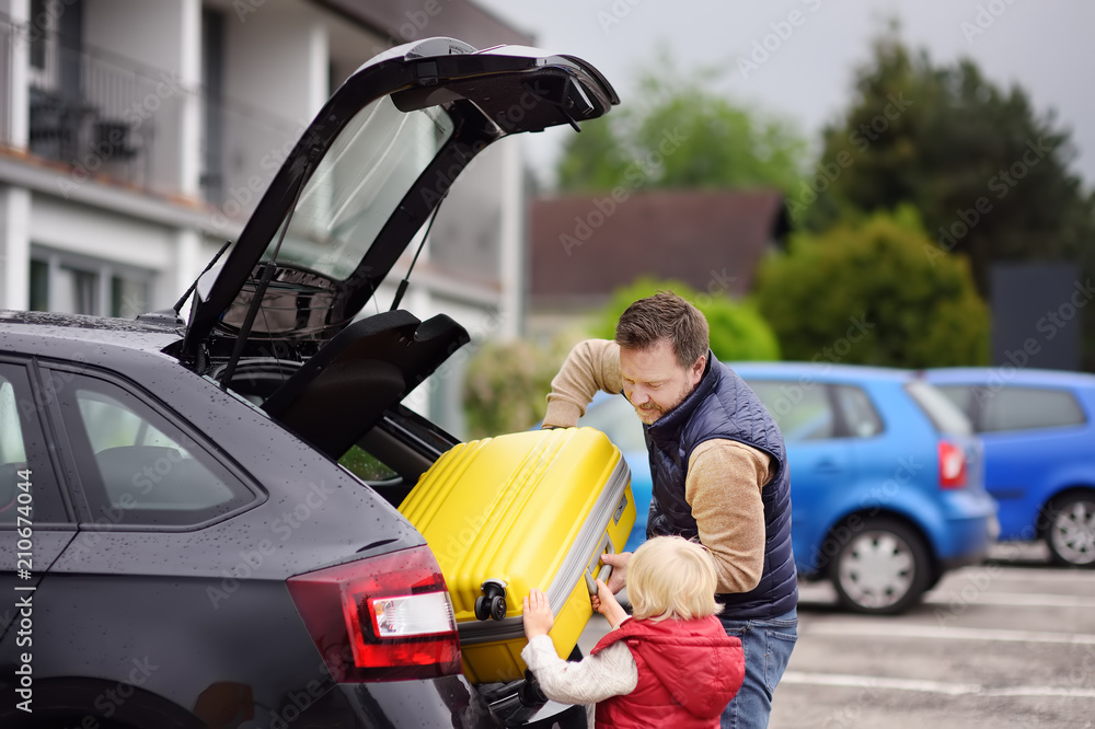 Handsome man and his little son going to vacations, loading their ...