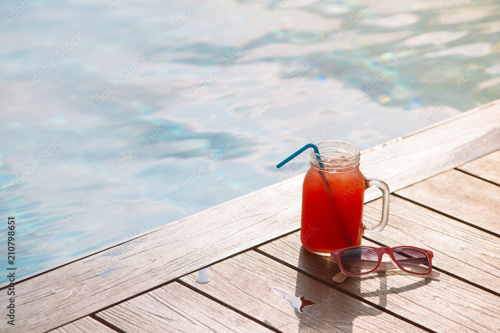 Glass of fresh watermelon smoothie juice drink on border of a swimming ...