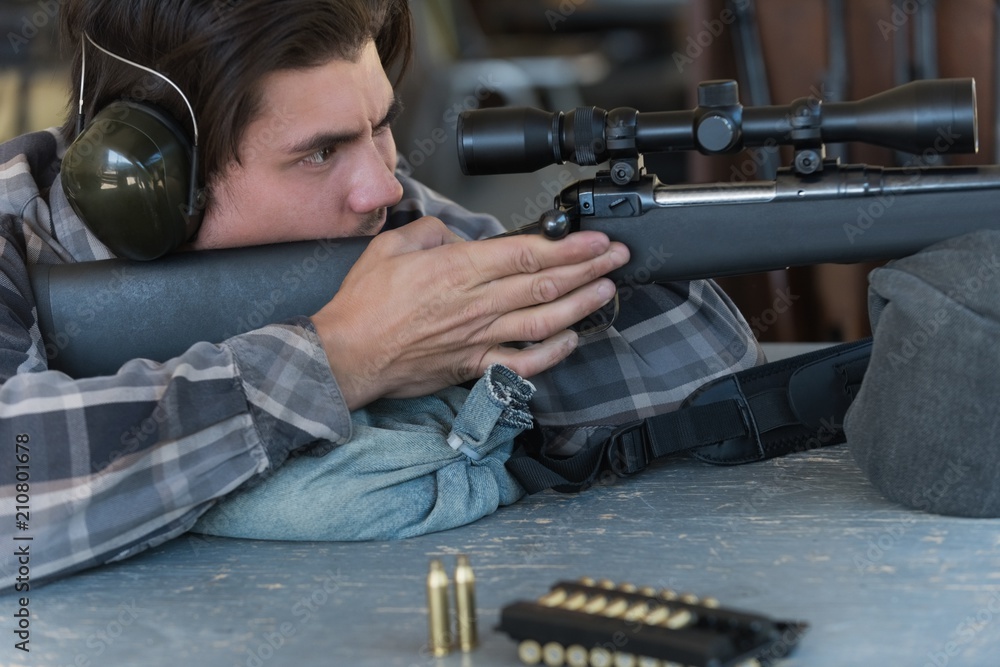 Man aiming sniper rifle at target in shooting range Stock Photo | Adobe ...