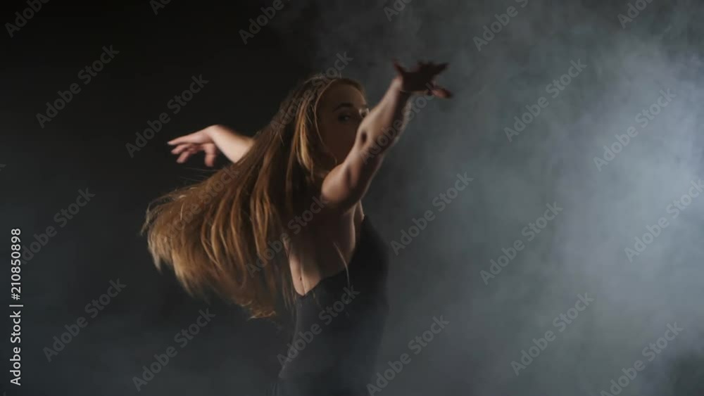 Professional ballerina dancing ballet in spotlights smoke on big stage ...