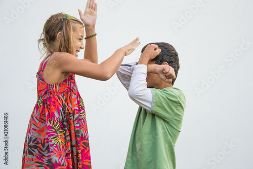Angry child girl beating gypsy boy violently with rage he is covering ...