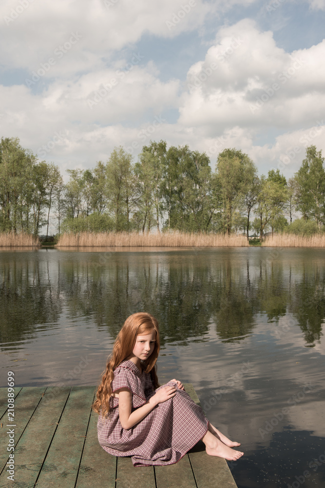 Serious girl sitting on dock Stock Photo | Adobe Stock