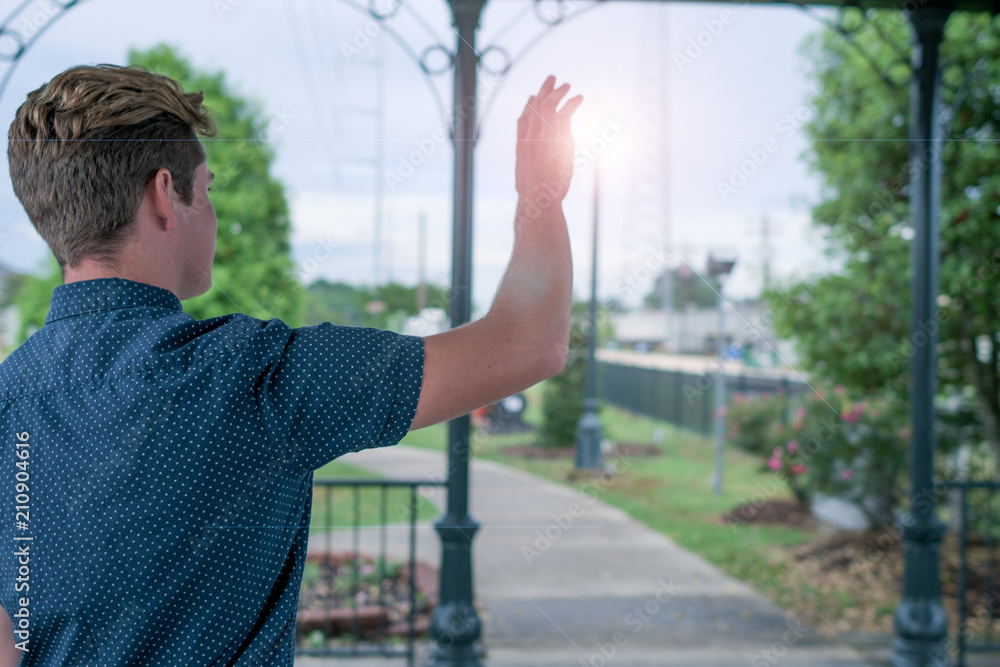 A young man slowly extends his arm up and outward moving his hand ...