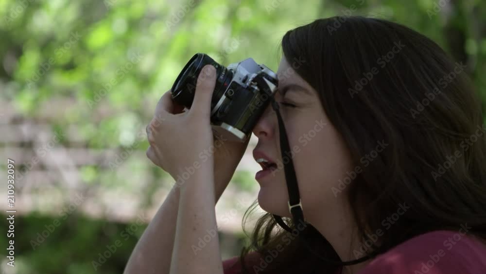 Young woman looks up and raises camera to take photo focusing up in the ...