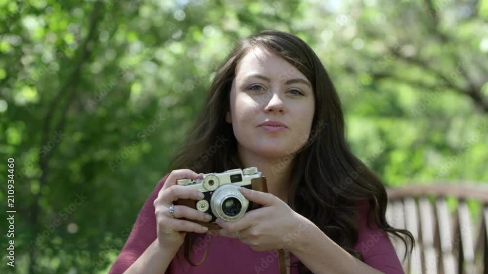 Young woman winding film on camera to take vertical photo looking ...