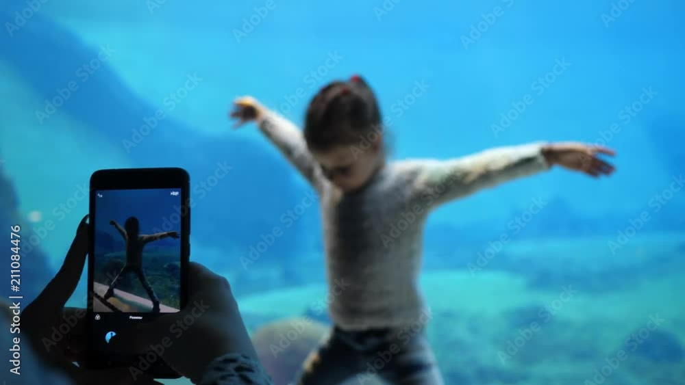 Mother takes mobile phone pictures of little child girl daughter pose ...