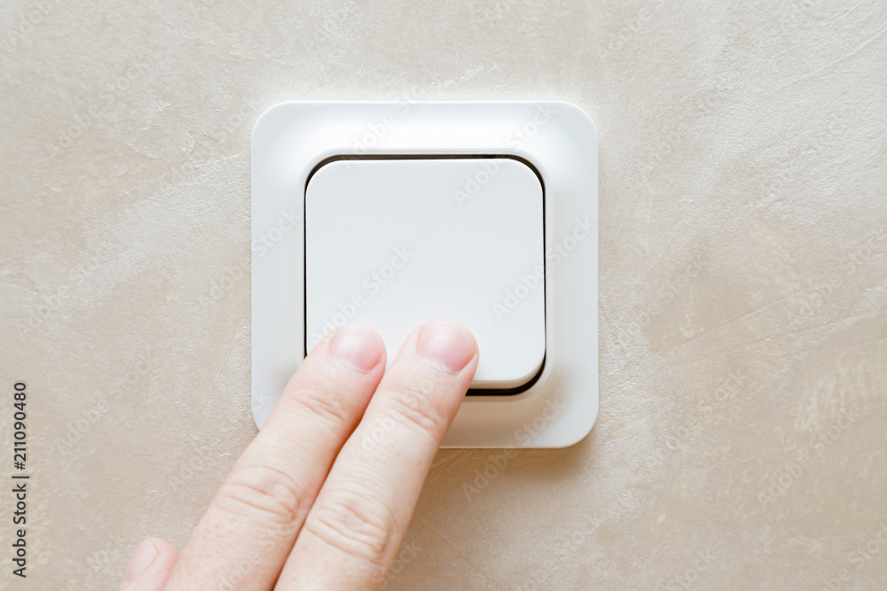 Man's fingers pressing light switch at the wall. Save energy at home ...
