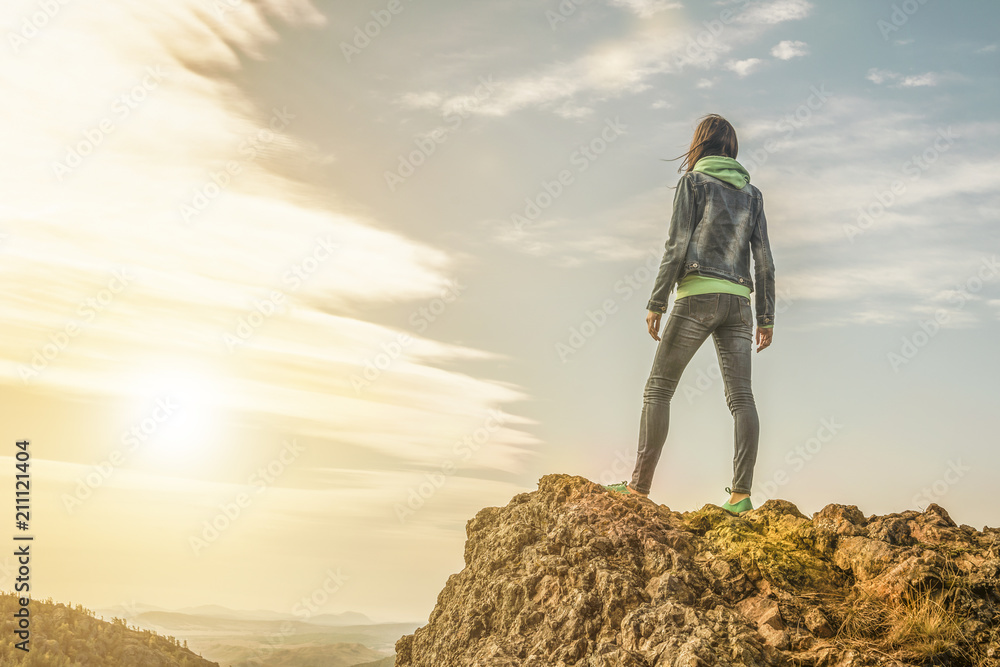 young girl standing on top of a mountain and enjoying the view of the ...