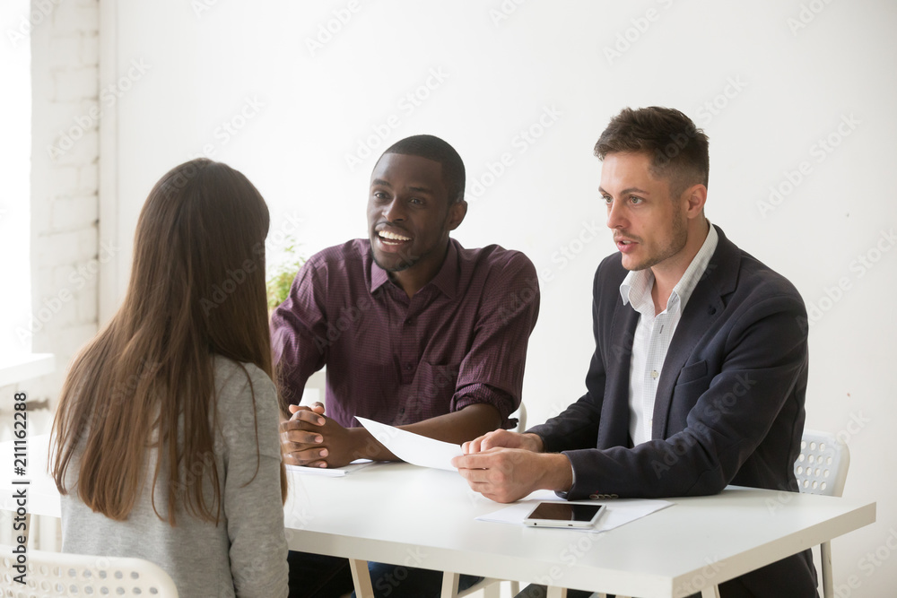 Friendly multiethnic hr team talking to female job candidate, reading ...