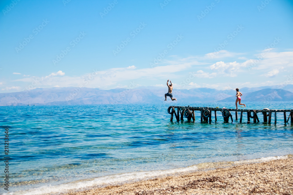 teenagers jumping off the pier into the sea. fun summer vacation.Young ...