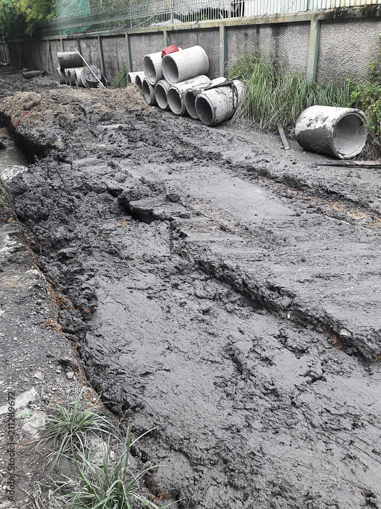 Concrete storm water drain pipes lay stacked on raw earth awaiting ...