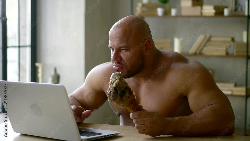 bald male bodybuilder writes a text on a laptop to comply with the ...