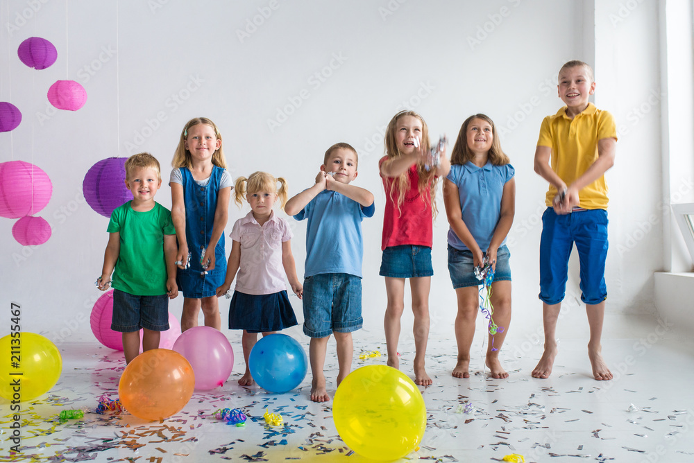 Group of seven 7 children play with air balloons, confetti in light ...