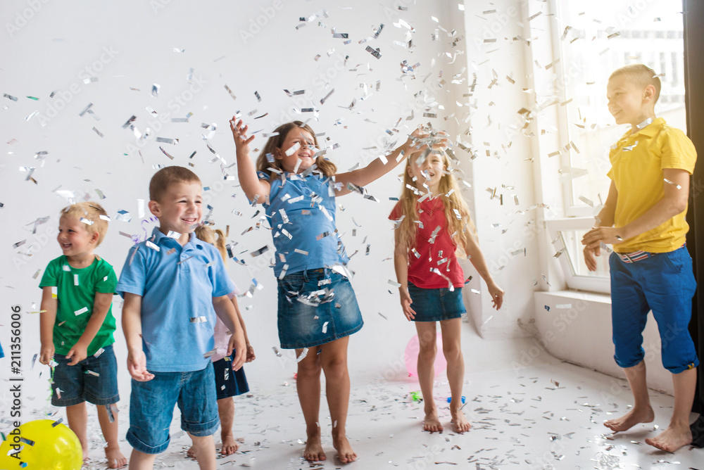 Group of 7 seven children play with air balloons, confetti in light ...