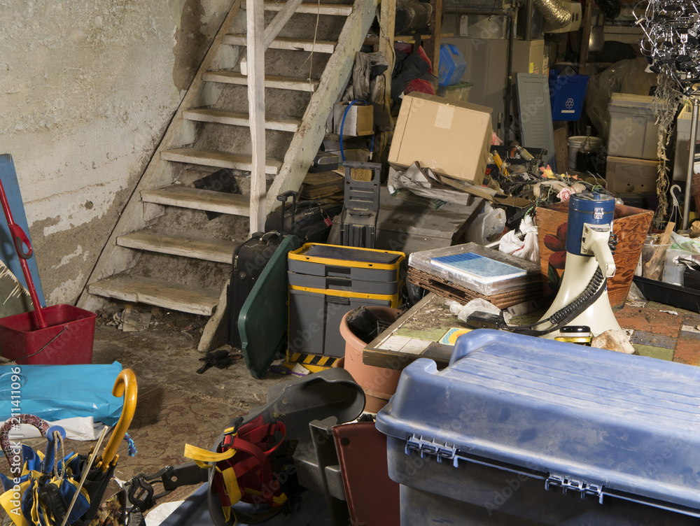 Old dingy residential unfinished basement cluttered with storage of ...