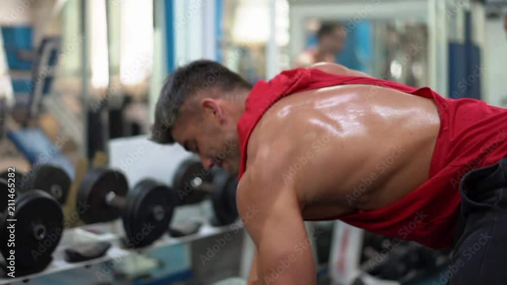 Bodybuilder man trains squat with dumbbells inside gym. Young ...