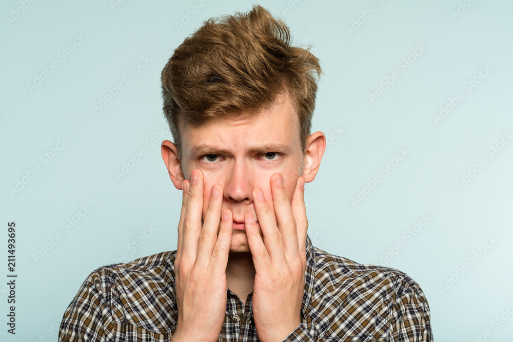 sad rueful depressed cheerless man covering his face in hands. portrait ...