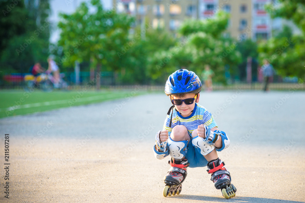 Little boy riding on rollers in the summer in the Park. Happy child in ...