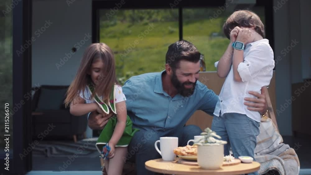 Playful likable Caucasian young man having fun with daughter and son ...