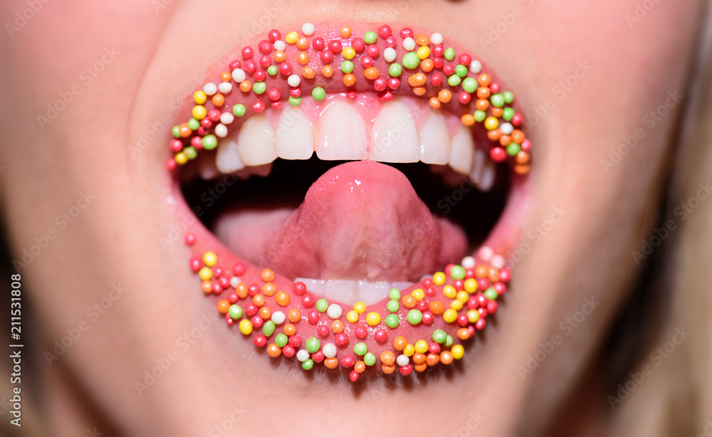 Sweet woman lips covered by candies. Sexy tongue. Young female plays ...