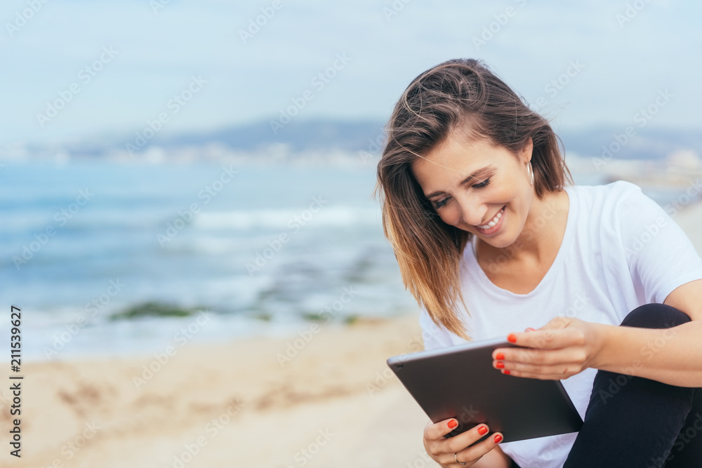 Young woman sitting reading on her tablet pc Stock Photo | Adobe Stock