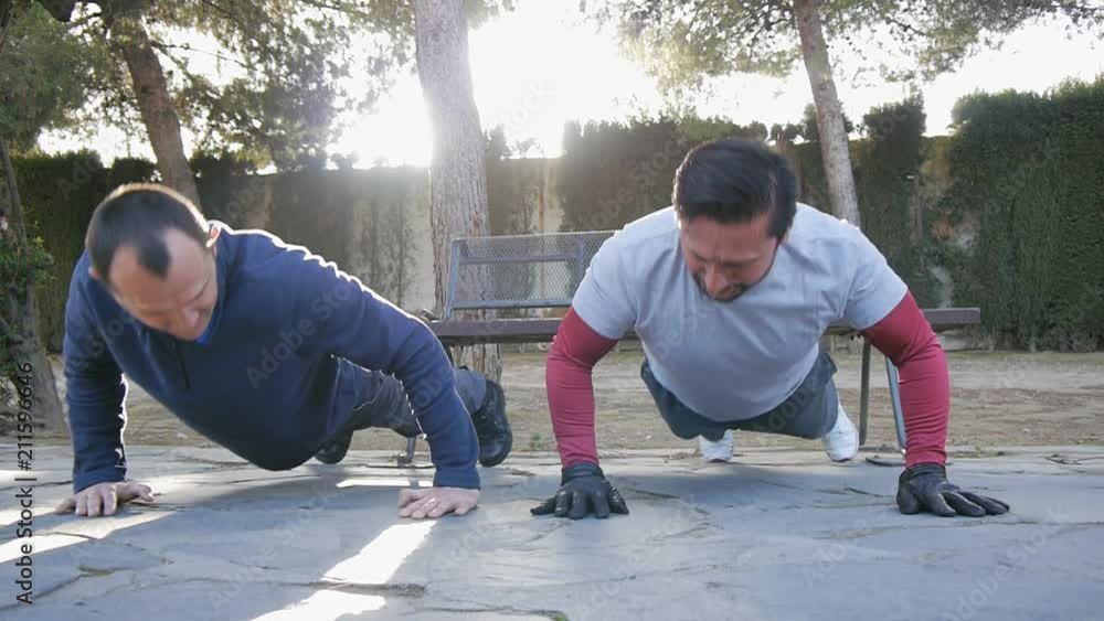 Workout with personal trainer outdoors. Two male athletes doing offset ...