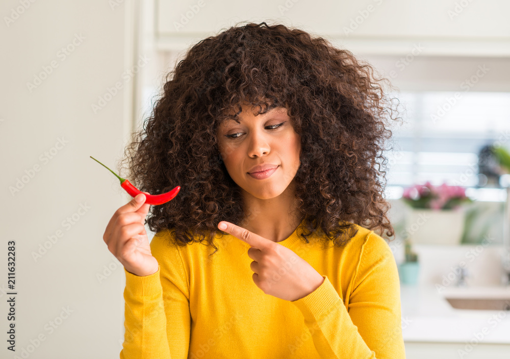 African american woman eating red hot chili pepper very happy pointing ... African american woman eating red hot chili pepper very happy pointing ...