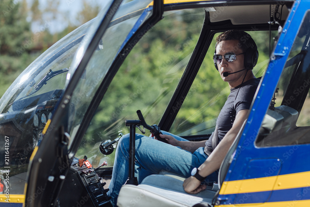Skilled professional. Athletic young pilot sitting at a pilot booth of ...