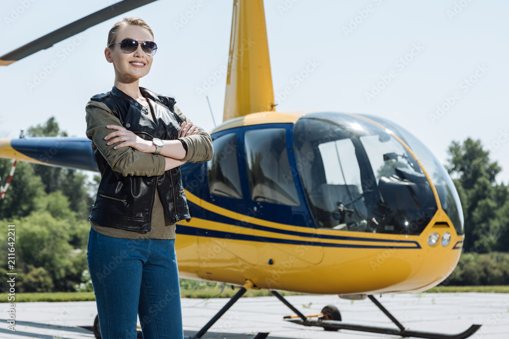 Proud female pilot. Charming female pilot folding her arms across her ...